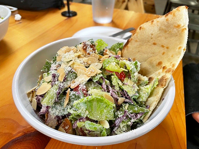 A Caesar salad that refuses to be a boring obligation. That piece of pizza crust perched on top is saying, "Yes, I'm still a pizza place. Don't forget it."