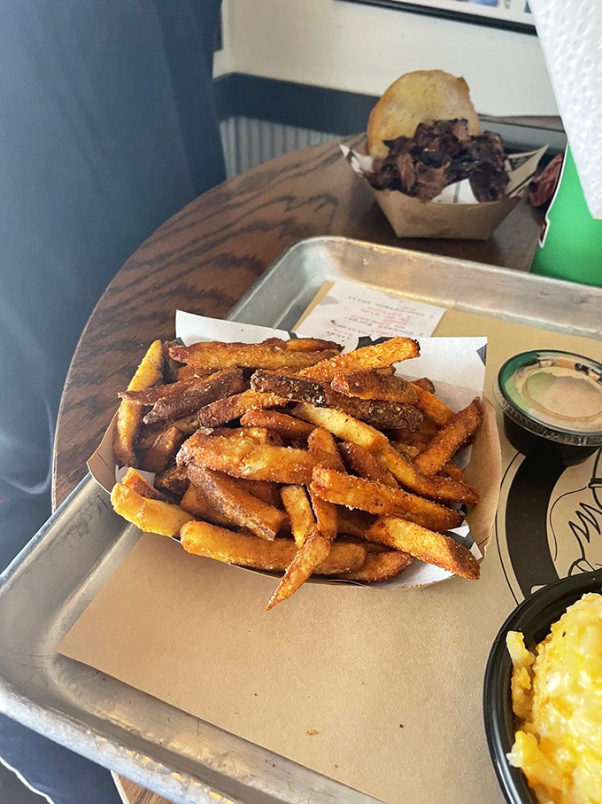 Fries that have clearly earned their PhD in crispiness, served alongside what appears to be pulled meat and mac and cheese—the holy trinity of comfort.