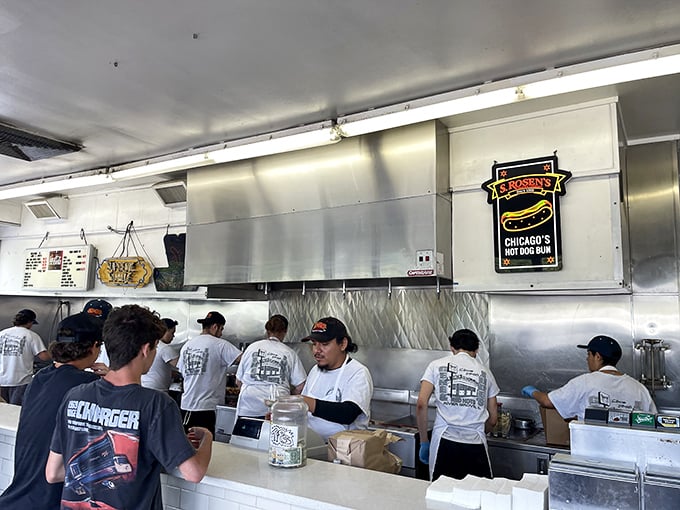 The kitchen crew moves with the choreographed efficiency of a Broadway ensemble, each person knowing exactly where they fit in the hot dog ballet.