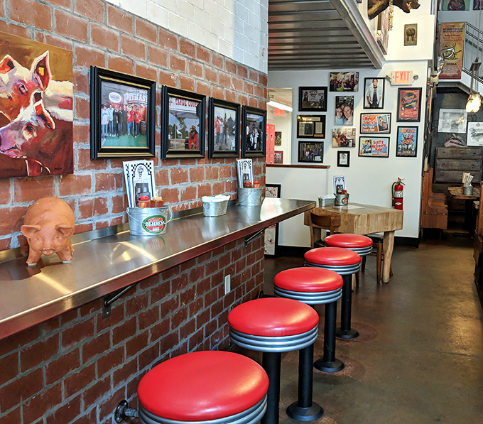 Red stools line the counter where regulars perch, watching the choreography of Carolina's barbecue tradition unfold.
