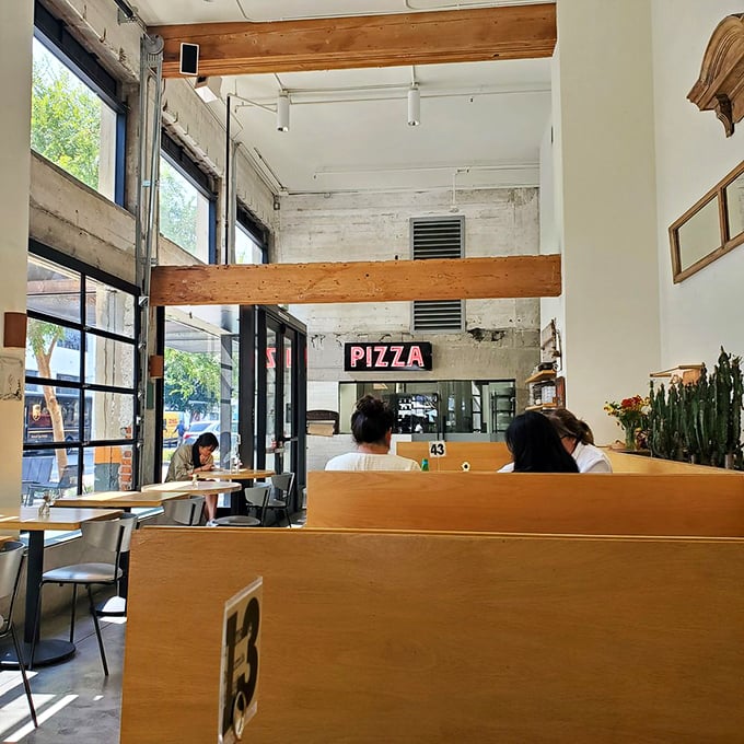 The simple "PIZZA" sign says everything necessary. In this light-filled space, diners commune with dough like it's a religious experience.