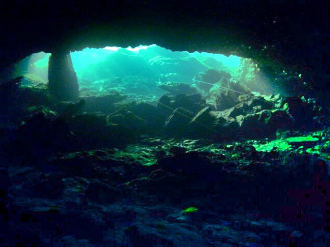 Sunlight pierces the darkness of an underwater cave, creating a light show worthy of a Pink Floyd concert.