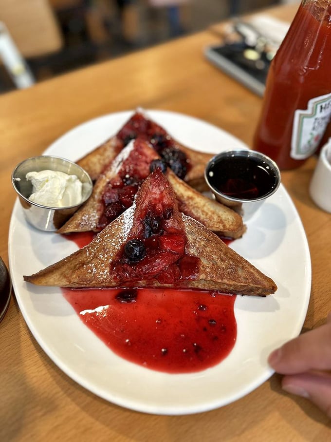 French toast swimming in berry compote—breakfast's answer to dessert. The small cup of cream is not optional.