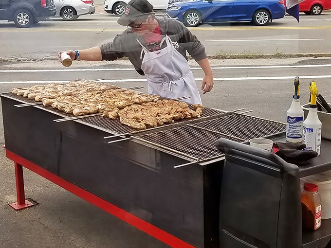 Chicken sizzling on the outdoor grill, tended by careful hands. This isn't just cooking—it's a public performance art where smoke signals announce deliciousness is imminent.