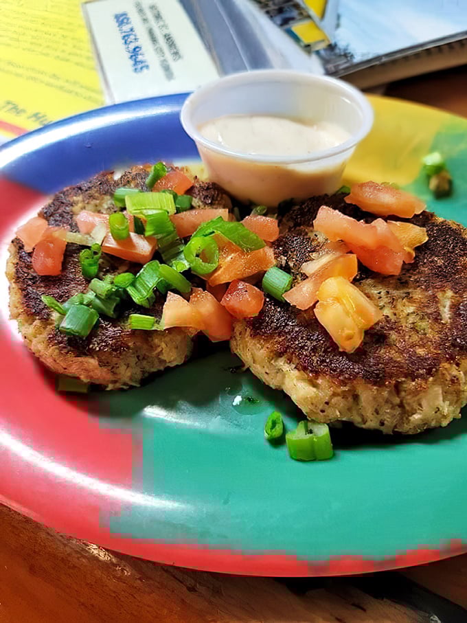 These crab cakes are what happens when someone respects the crab—minimal filler, maximum flavor, topped with fresh tomato and scallions.