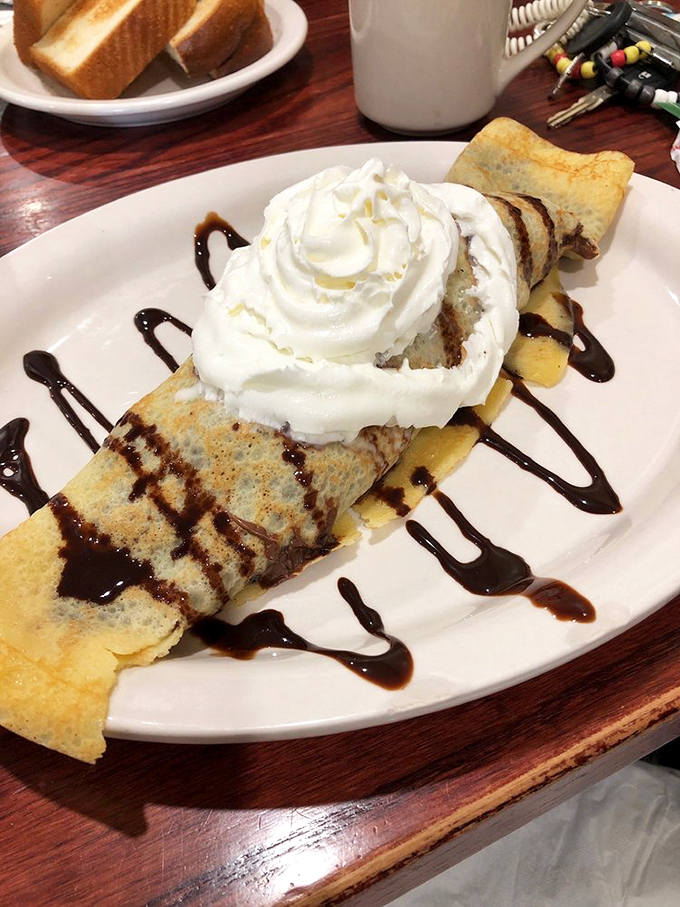 This crepe isn't just dessert, it's performance art. Chocolate drizzle and whipped cream turning breakfast into an occasion.