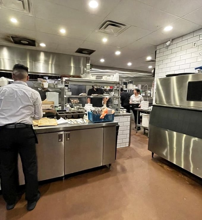 The kitchen's gleaming stainless steel and pristine white tile reveal the serious culinary commitment behind every seemingly effortless dish.