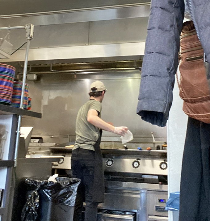 The wizard behind the curtain—a glimpse into the kitchen where breakfast magic happens on a well-seasoned flat-top grill.