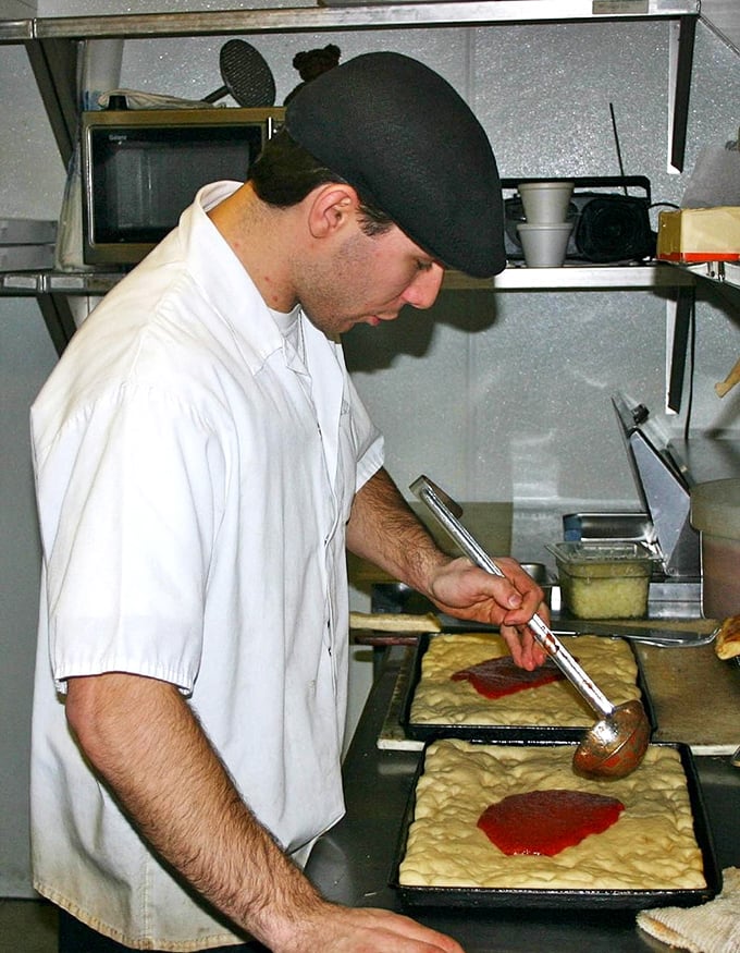 Behind the scenes, the pizza-making process reveals itself as part science, part art, and all tradition—each tray built with practiced precision.