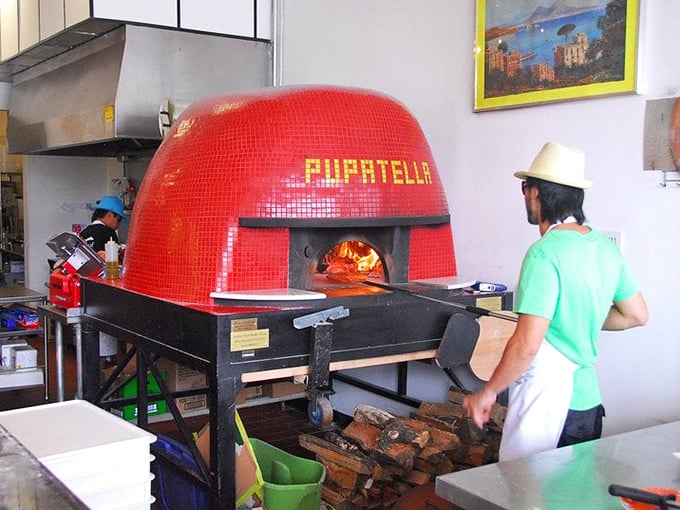The fiery heart of Pupatella—a magnificent red-tiled oven that transforms simple ingredients into edible masterpieces at 900 degrees. 