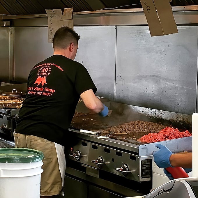 The grill master at work, tending to sizzling meat with practiced precision. Decades of experience translate into each perfectly crafted sandwich.