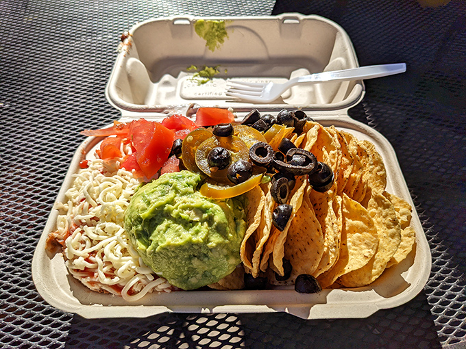 Nachos that understand the importance of proper topping distribution. That guacamole mound isn't just a condiment—it's the emerald crown jewel. 