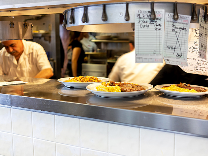 Where the magic happens: skilled hands preparing multiple plates simultaneously, a choreographed ballet of breakfast preparation.