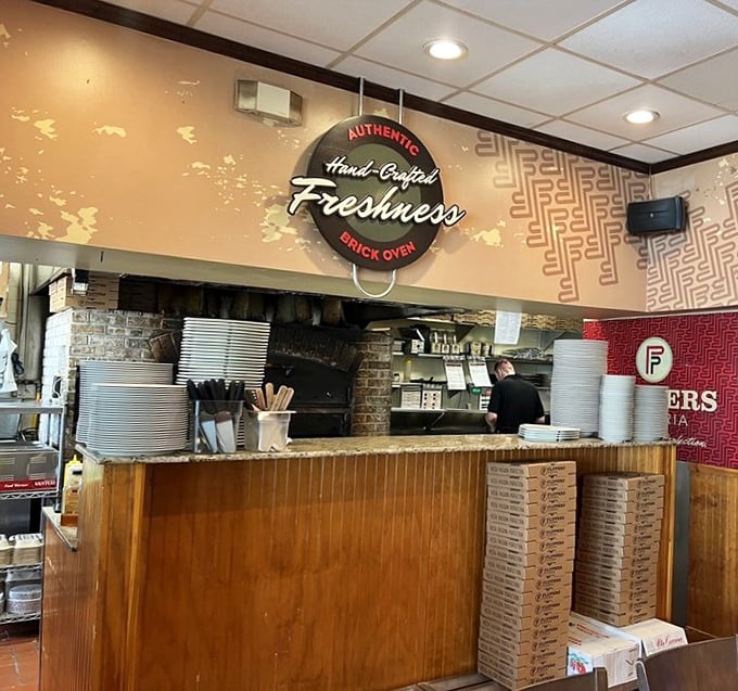 The open kitchen isn't just for show—it's pizza theater where dough-tossing artisans craft your dinner with brick oven precision.