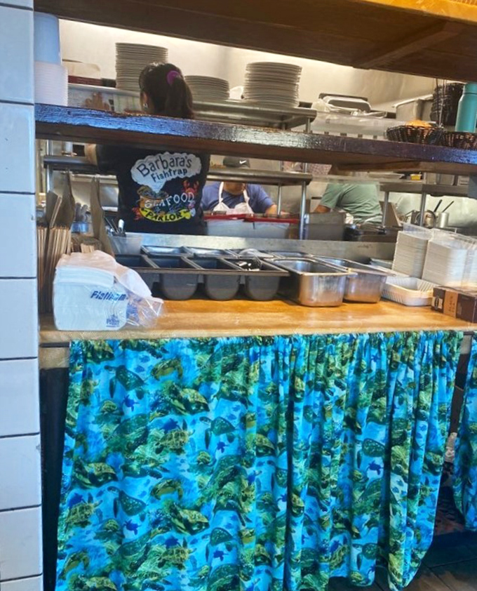 Behind the scenes, staff in fish-patterned curtains orchestrate seafood symphonies. The kitchen's blue and green palette mirrors the ocean's bounty.