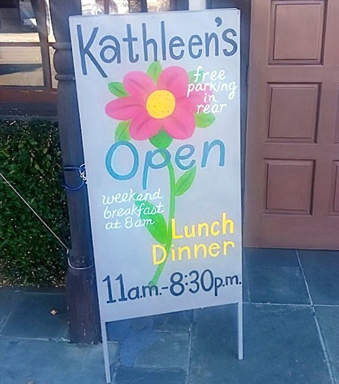 The cheerful sidewalk sign with its hand-drawn flower – somehow more inviting than any slick digital display could ever be.