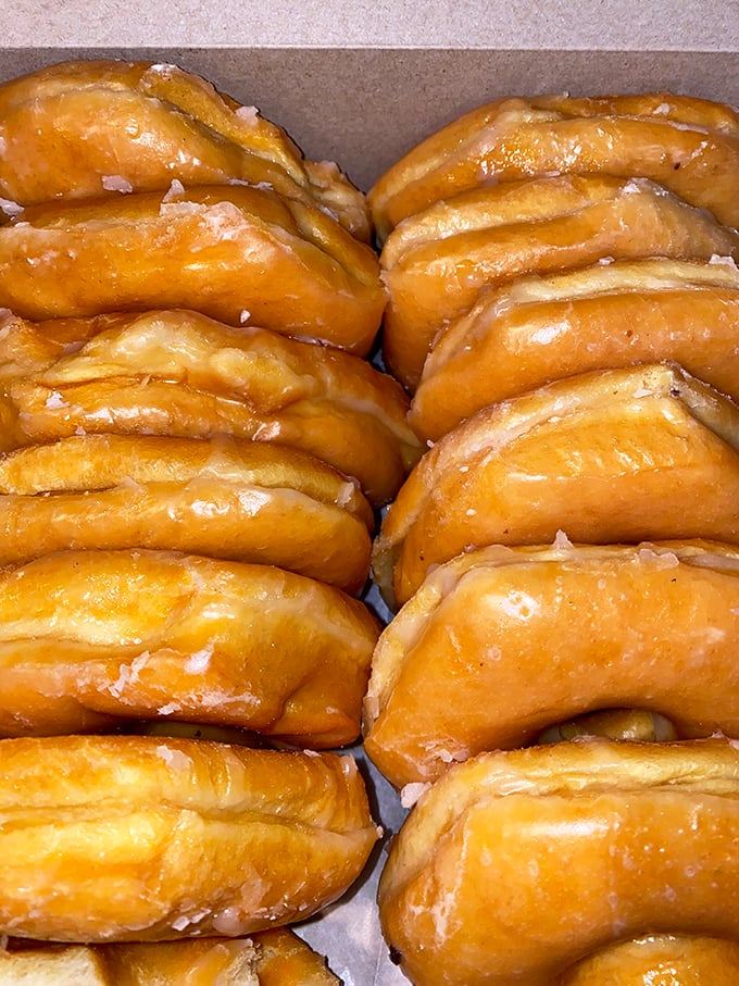 Glazed donuts lined up like soldiers, ready for duty. Their mission: bringing joy, one bite at a time.