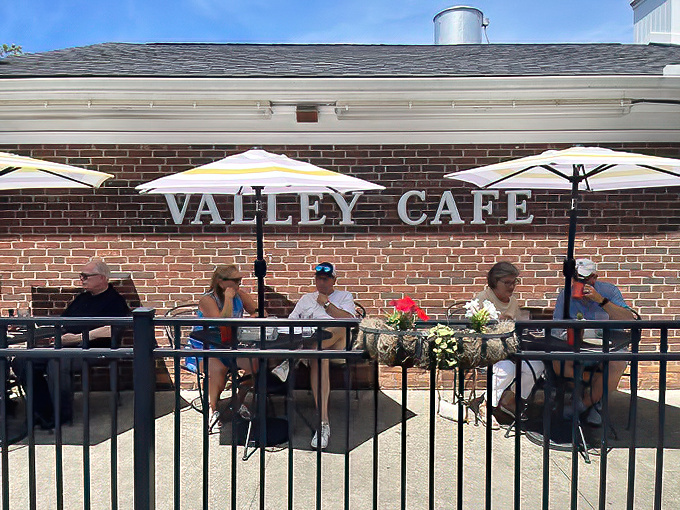 Outdoor seating where strangers become temporary neighbors, united under yellow umbrellas by their mutual love of excellent food.