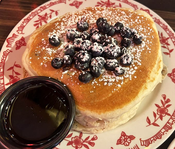 These pancakes don't just come with blueberries – they wear them like jewelry. The powdered sugar snowfall is just showing off.