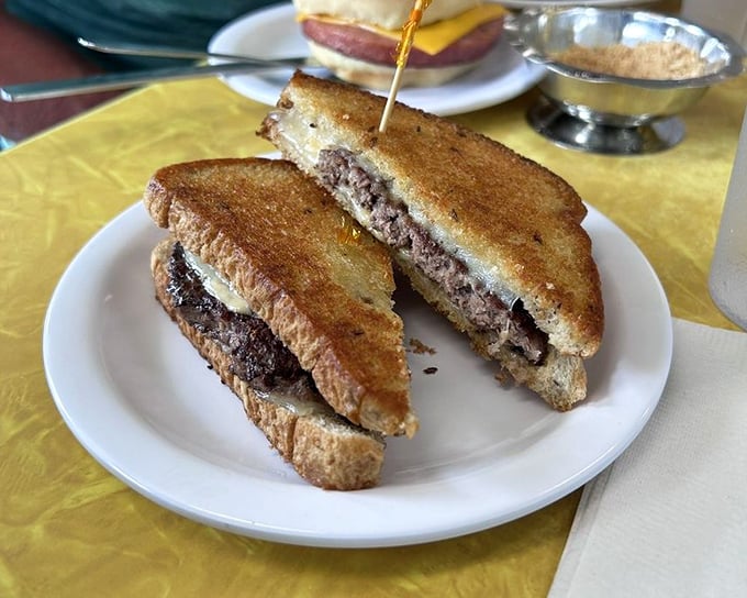The patty melt—that brilliant compromise between burger and grilled cheese—reveals its beefy soul in a cross-section worthy of a food museum.
