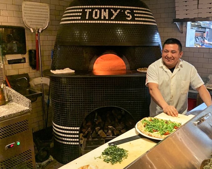 The maestro at work! That wood-fired oven isn't just cooking equipment—it's a time machine transporting you straight to Naples.