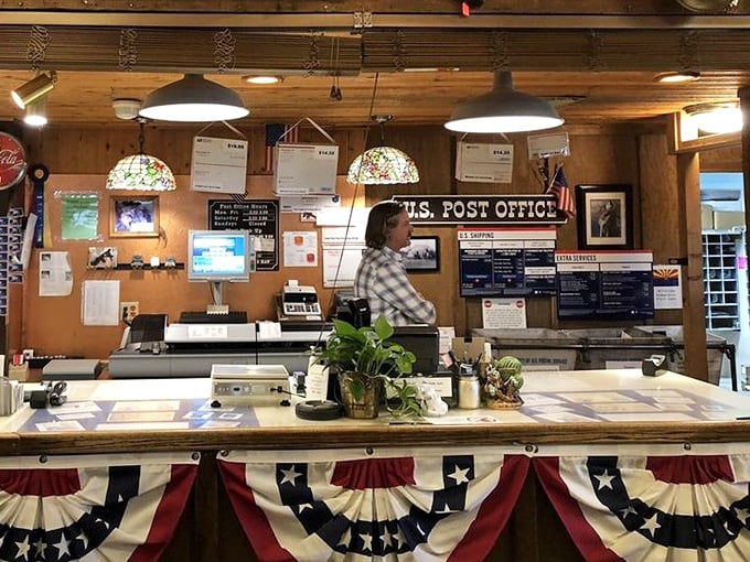 The post office counter, adorned with patriotic bunting, serves as a reminder that this place delivers more than just great sandwiches.