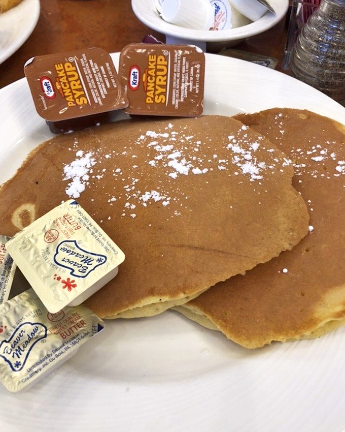 These pancakes aren't just breakfast—they're edible frisbees of joy, dusted with powdered sugar and waiting for their maple syrup baptism.