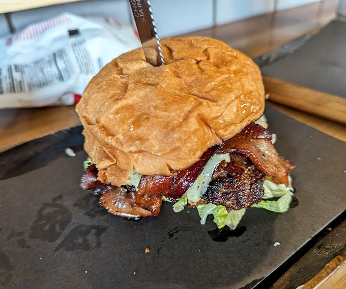The Oakwood burger doesn't just sit on its plate—it commands attention. That perfectly toasted bun cradles its contents like a mother holding her delicious, bacon-topped child.