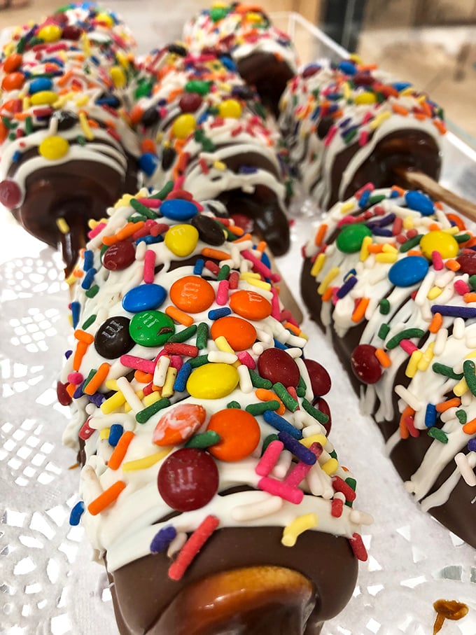 These chocolate-dipped waffle sticks adorned with sprinkles and candy aren't just desserts—they're portable shopping fuel disguised as justifiable indulgences.
