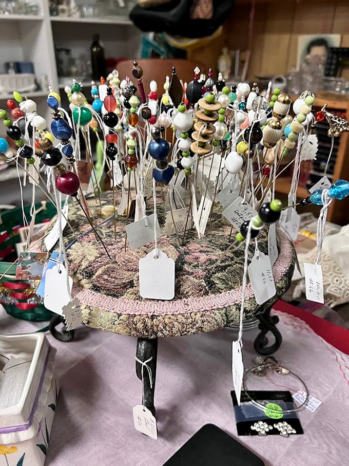 A pincushion forest blooms with colorful vintage hat pins, each tiny globe a miniature world of craftsmanship rarely seen in modern accessories.