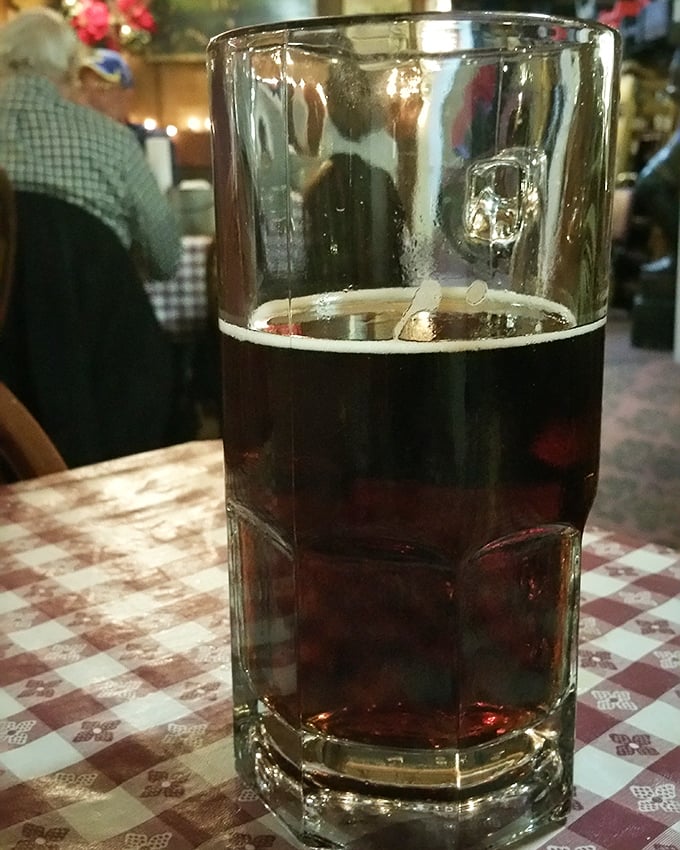 A proper glass of dark beer on a checkered tablecloth – because sometimes the perfect dining companion doesn't need conversation.