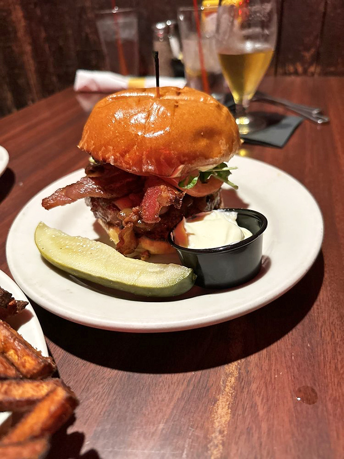 This bacon-topped burger isn't just food—it's architecture. The pickle stands guard like it's protecting a national treasure.