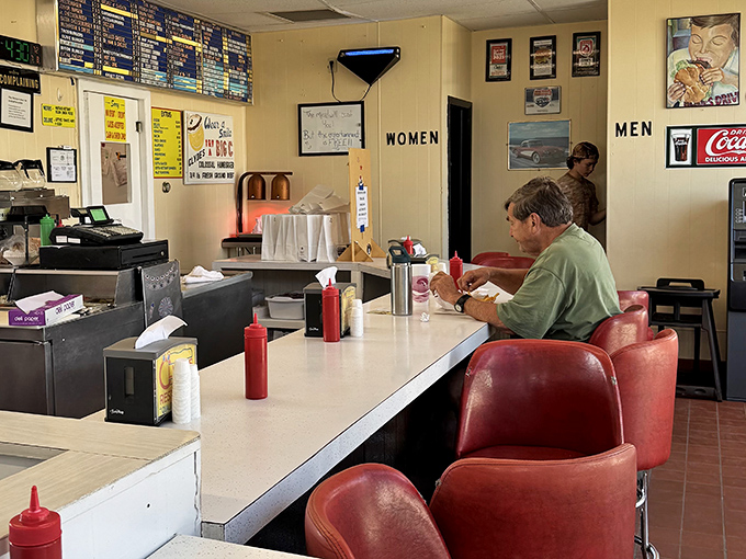 Solo dining at the counter—a Michigan tradition. That red squeeze bottle stands ready, like a loyal sidekick to your burger adventure.