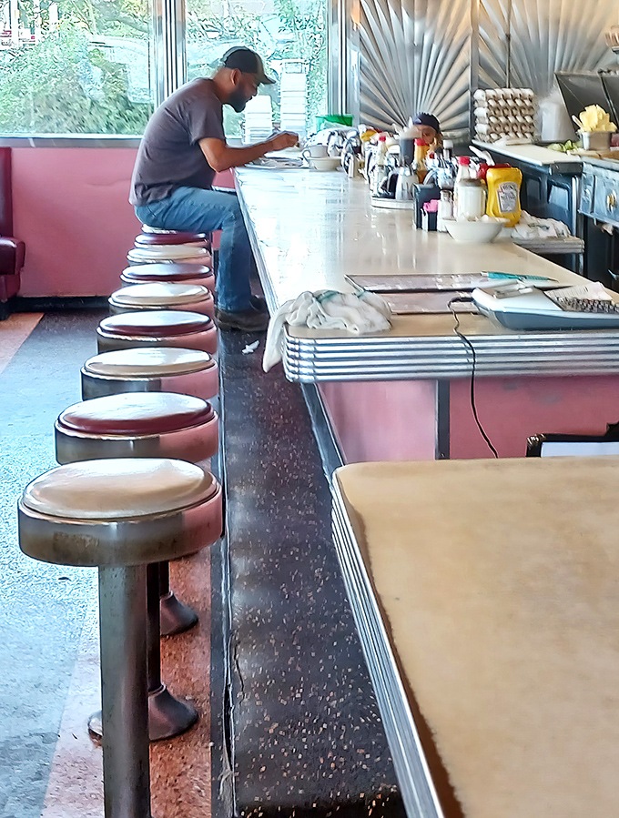 The counter—where solo diners find community, newspapers get thoroughly read, and coffee refills flow with blessed regularity.
