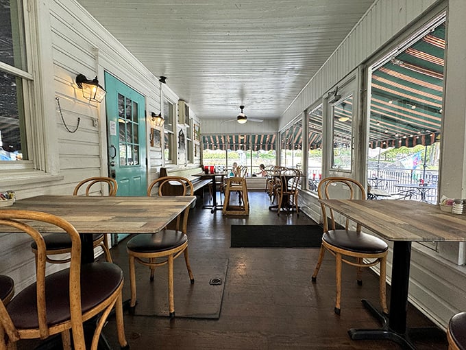 A screened porch that captures summer's essence – where wooden tables and vintage chairs invite you to linger over coffee long after your plate is clean.