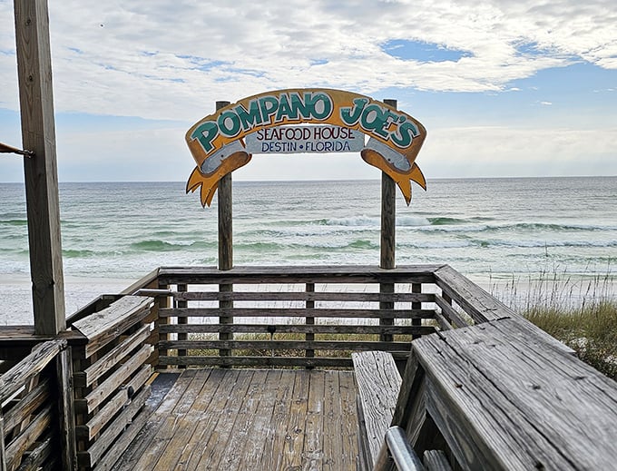 The wooden deck offers front-row seats to nature's greatest show. That sign isn't just announcing a restaurant—it's promising memories that outlast your sunburn.