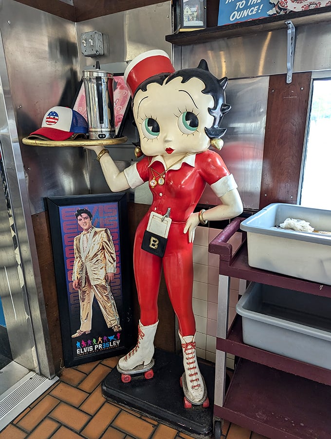 Betty Boop stands eternal watch over the diner, roller skates ready, with Elvis keeping her company—guardians of American pop culture in this temple of comfort food.