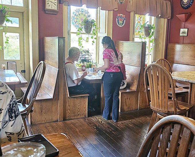 Cozy wooden booths bathed in natural light create intimate dining spaces. The kind of spot where conversations flow as easily as the coffee.