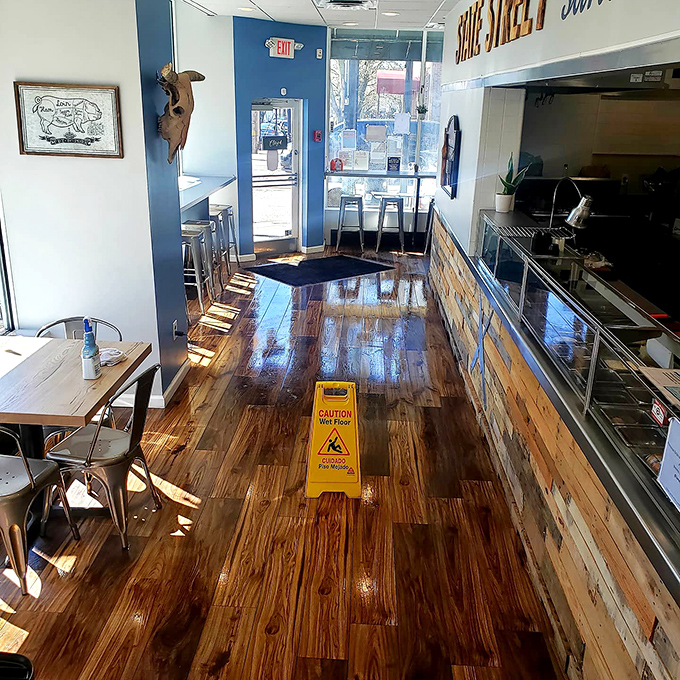 Polished wood floors reflect the sunlight streaming in, creating the perfect backdrop for the sandwich artistry happening behind the counter.