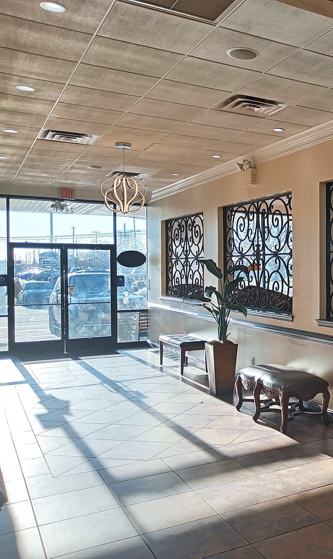 Sunlight pours through the entrance, highlighting decorative ironwork and potted plants. First impressions matter, especially before coffee.