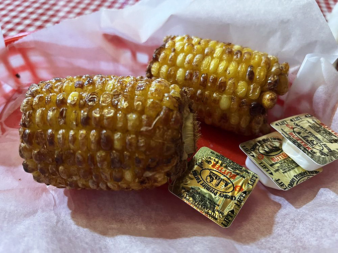 Grilled corn on the cob with butter packets standing by – nature's perfect hand-held side dish waiting for its moment in the spotlight.