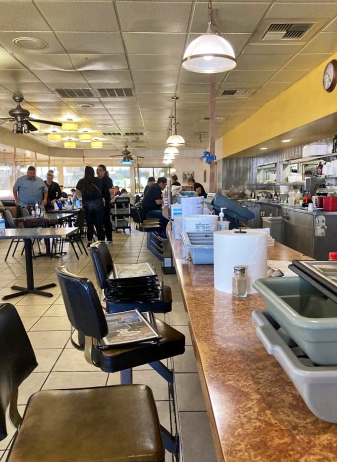 The counter seats—where breakfast solo artists perform their morning rituals while watching the kitchen's choreographed chaos create edible masterpieces.