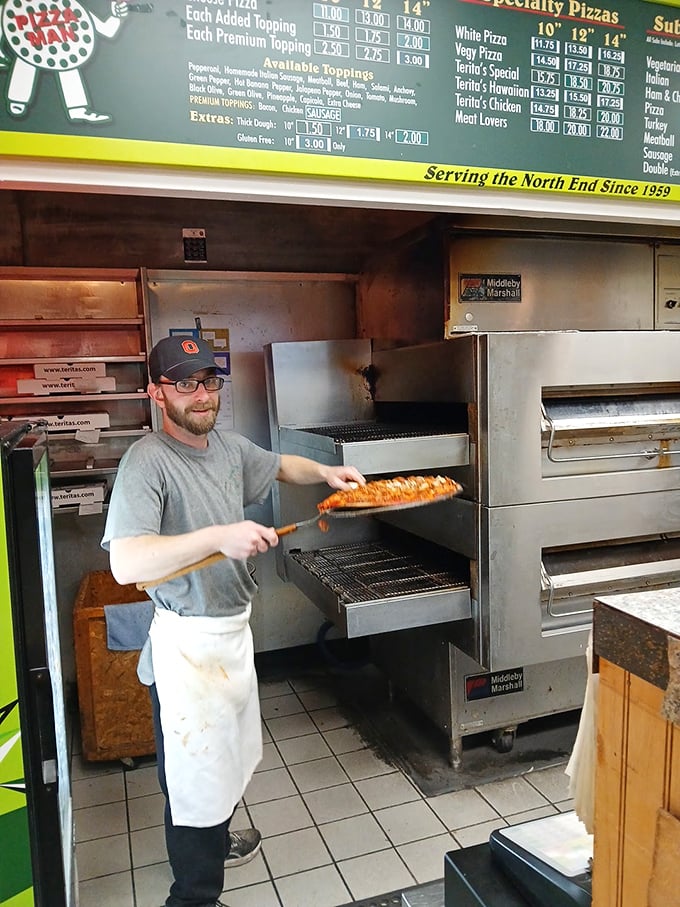 The pizza-making process on display – a skilled hand wielding the pizza peel with the confidence that comes from thousands of perfect pies.