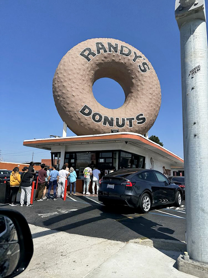 The line forms under the watchful eye of the great donut. Some wait for concert tickets, others for celebrities – the wise wait for Randy's.