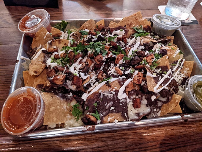 These aren't your ballpark nachos—they're an architectural masterpiece of layers, textures, and flavors that demand to be shared but tempt you not to.