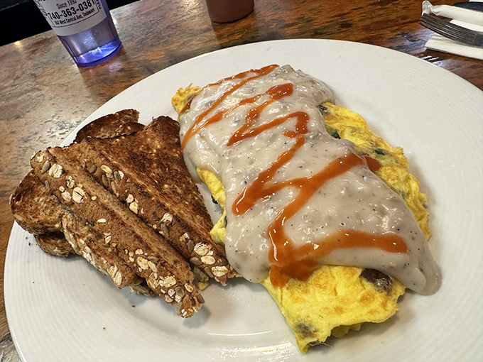 An omelet draped in country gravy with hot sauce racing stripes—breakfast engineering at its finest.