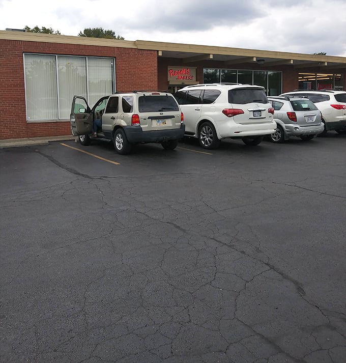 The parking lot – where cars gather like honeybees, drawn by the sweet promise of what waits inside those brick walls.