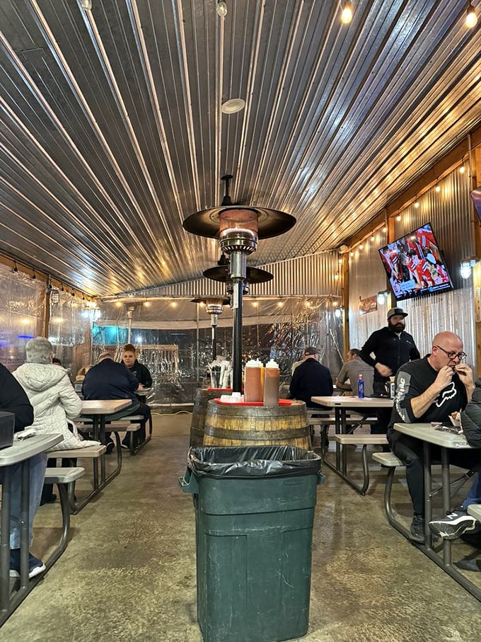 The corrugated metal ceiling and barrel tables create a covered patio experience that feels like the VIP section of a backyard barbecue.