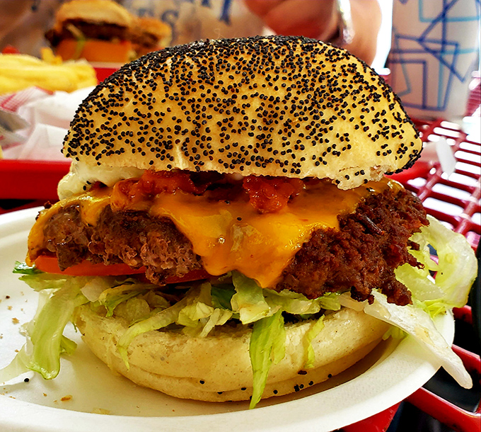 A poppy seed bun crowns this masterpiece like jewels on royalty. The melted cheese cascades down the sides in a glorious golden waterfall.