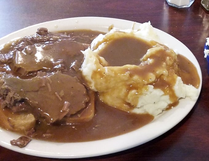 A hot roast beef sandwich that doesn't just sit on the plate—it commands respect with gravy cascading over the sides like a delicious waterfall.
